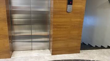 Um elevador com mostrador digital, painel de madeira e chão de mármore com design circular.
