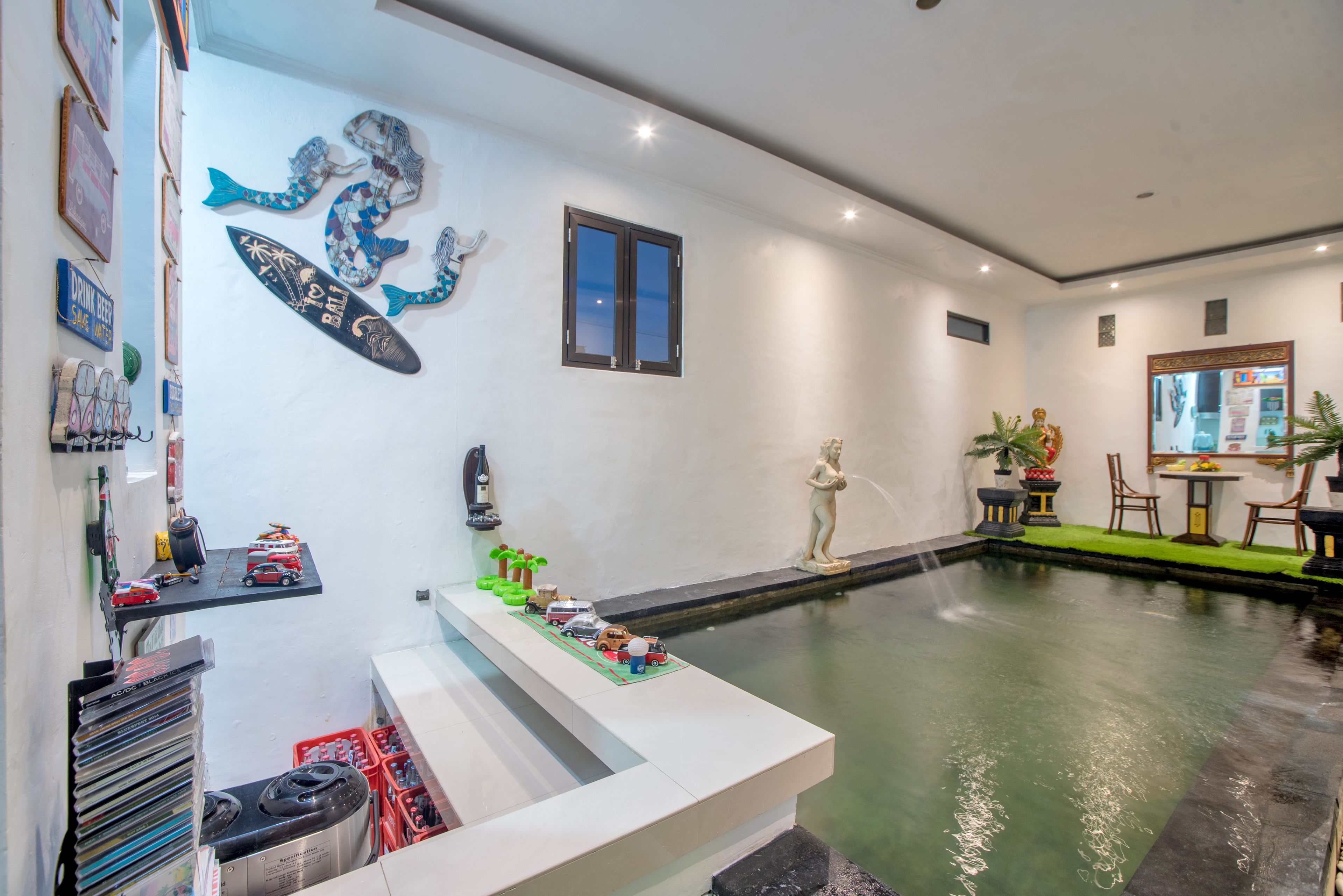 Um saguão de hotel com piscina, um mural de sereias e uma estátua.