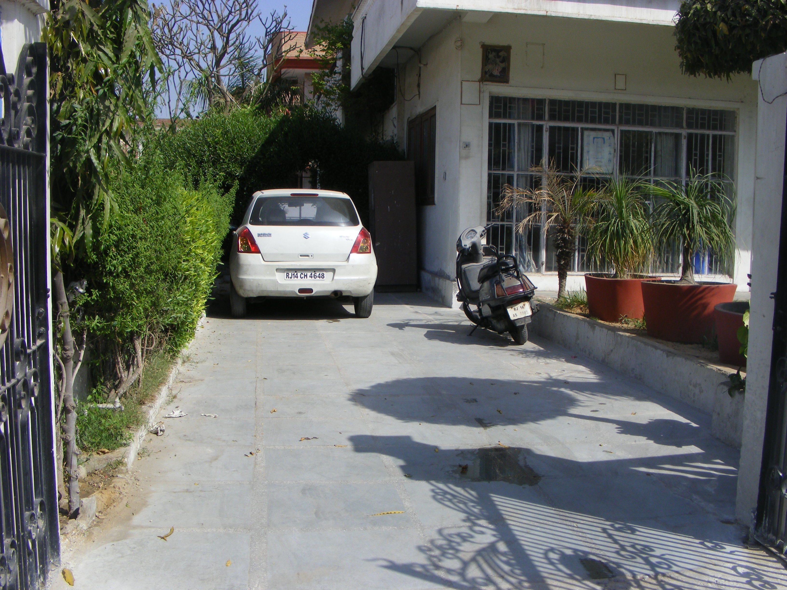 Uma entrada estreita leva a uma casa com um carro e uma motocicleta estacionados.