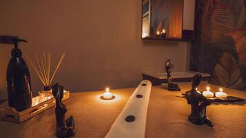Um quarto com uma toalha branca comprida, velas e objetos decorativos sobre uma mesa de madeira.
