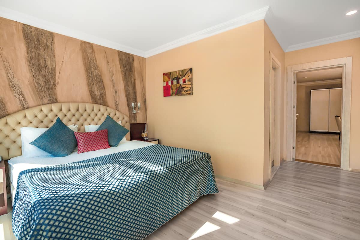 Quarto com cabeceira estofada, colcha estampada e um quadro na parede.