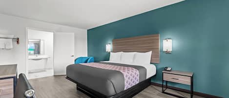 Quarto de hotel moderno com cama, mesa de cabeceira e vista para o banheiro.