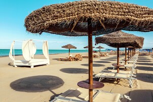 Praia particular, areia branca, espreguiçadeiras, guarda-sóis 