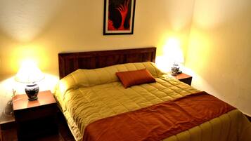 Uma cama com cabeceira de madeira, duas luminárias laterais e um quadro na parede.