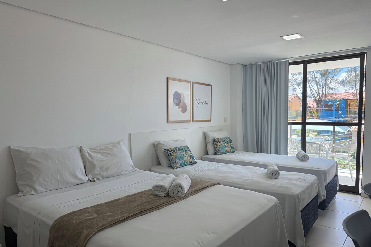 Quarto de hotel com duas camas, uma janela grande e vista, e uma luminária no teto.