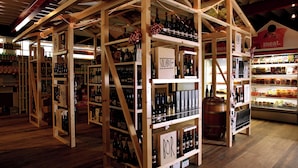 Uma loja de vinhos com prateleiras de madeira e um balcão de carnes.