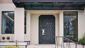 Entrada de um edifício moderno com uma porta preta grande, acesso de vidro e uma escadaria.