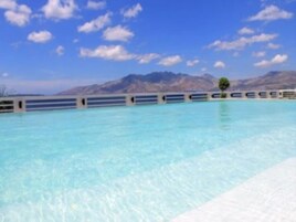 Piscina azul cristalina com vista para montanhas ao fundo.