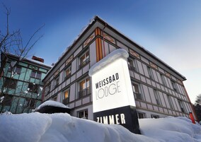 Um edifício com uma placa que diz 'WEISSBAD LODGE ZIMMER'.