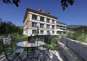 Um edifício com terraço, mesas ao ar livre e vista para as montanhas.