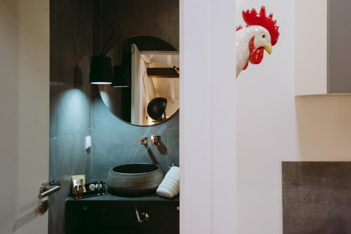Casa de banho com lavatório redondo, espelho e porta-toalhas.