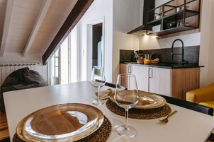 Uma cozinha moderna com armários de madeira, bancada preta e área de refeições com mesa branca posta para dois.