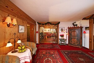 Um quarto acolhedor com decoração em madeira, uma área de refeições ao fundo e um tapete vermelho.