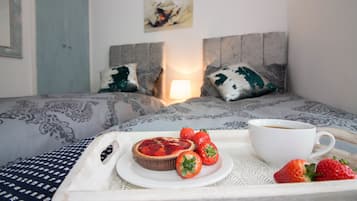 Cama com roupa de cama estampada, bandeja com uma torta, morangos e uma xícara de café.