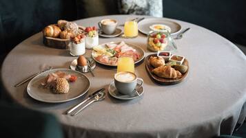 Uma mesa de jantar redonda com itens de café da manhã, uma xícara de café e uma garrafa de suco de laranja.