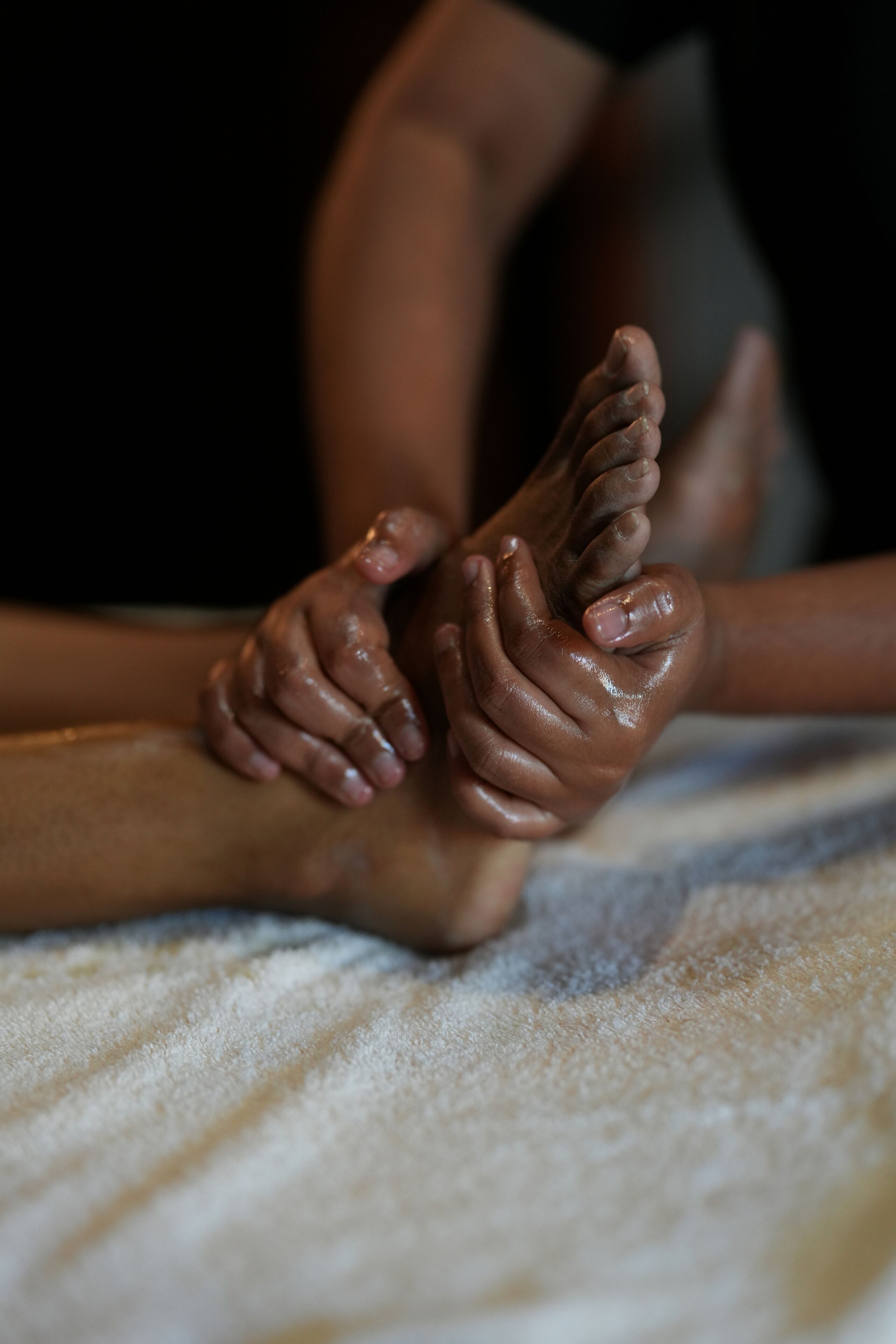 Close-up de mãos massageando os pés de alguém.