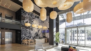 Um hall amplo com mobiliário moderno, balcão de recepção e grandes janelas.