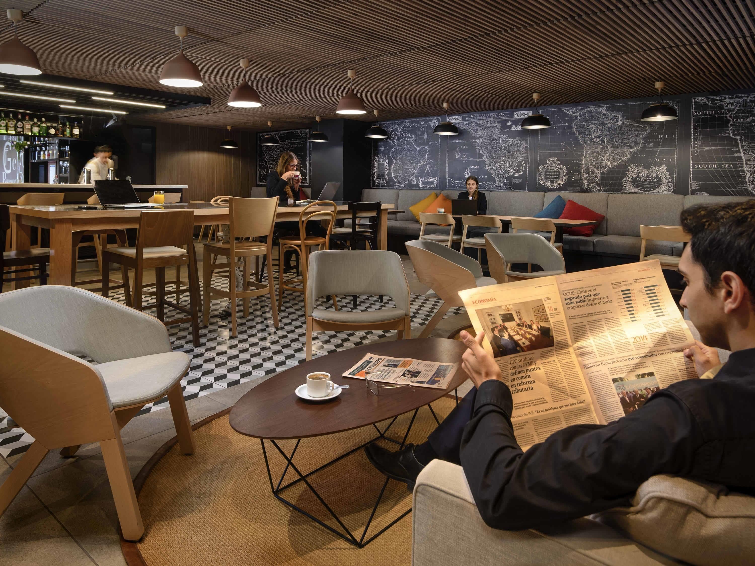 Uma área de estar moderna com mobiliário de madeira, piso xadrez e um bar ao fundo.
