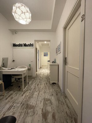 Um corredor com uma mesa, uma cadeira e uma placa com a inscrição 'Moshi Moshi'.