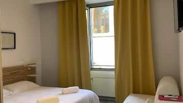 Quarto de hotel com duas camas, uma escrivaninha e uma cadeira.