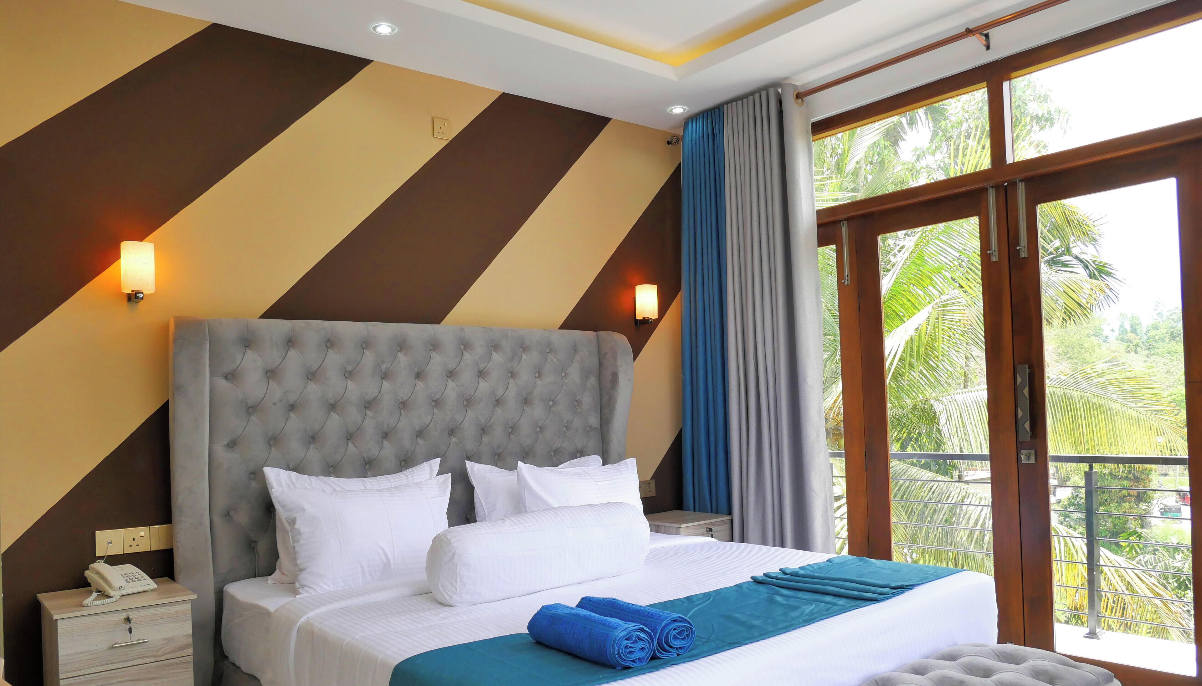 Quarto de hotel com uma cama grande, mesa de cabeceira, telefone e vista para áreas verdes pela janela.