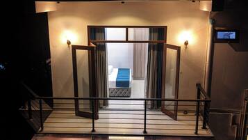 Quarto de hotel com cama, janela e escada que dá acesso ao quarto.