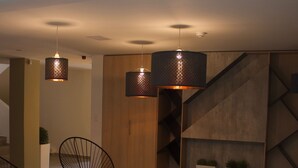 Um interior moderno com uma área de estar curvilínea, duas cadeiras de estrutura metálica e duas luminárias pendentes.