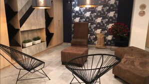 Um interior moderno com designs geométricos nas paredes, um sofá marrom e duas cadeiras vazadas pretas.