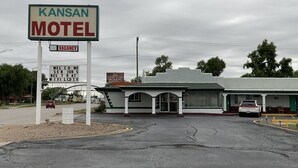 Um motel em Kansas, com uma placa, estacionamento e um edifício com telhado verde.