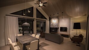 Uma sala de estar moderna com lareira, uma área de jantar e uma janela grande.