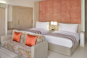 Quarto de hotel com duas camas, um sofá e um guarda-roupa.