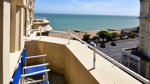 Uma varanda com vista para o mar, uma praia e um edifício com a placa 