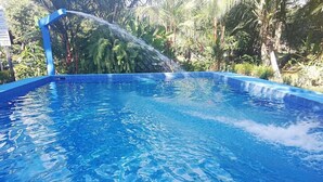 Piscina com água azul cristalina e um recurso aquático que jorra água para o ar.