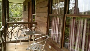 Uma cabana de madeira com varanda, uma mesa e duas cadeiras.