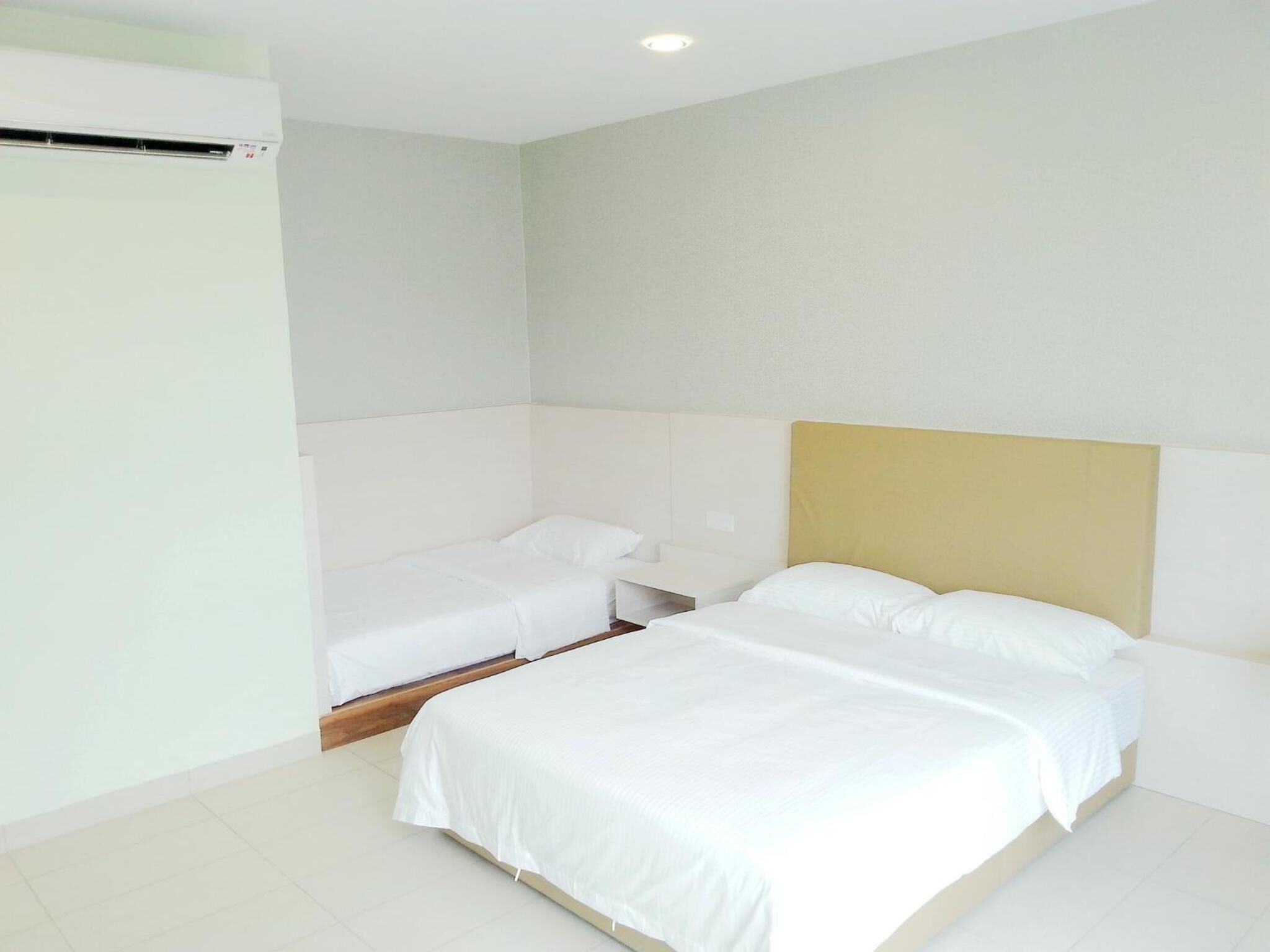 Quarto de hotel com duas camas, um ar condicionado branco e uma parede lisa.