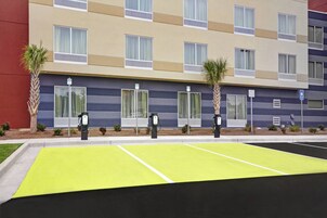 Hotel com área de estacionamento, estações de carregamento para veículos elétricos e palmeiras.