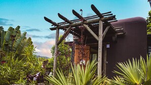 Estrutura rústica de madeira com pérgola, rodeada por exuberante vegetação tropical e um deck de madeira.