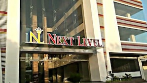 Entrada de hotel com uma placa que diz 'NEXT LEVEL'.