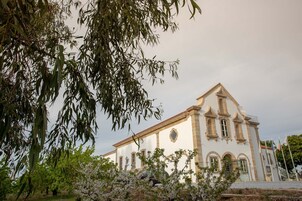 Um edifício histórico com fachada simétrica, janelas em arco e frontão central.