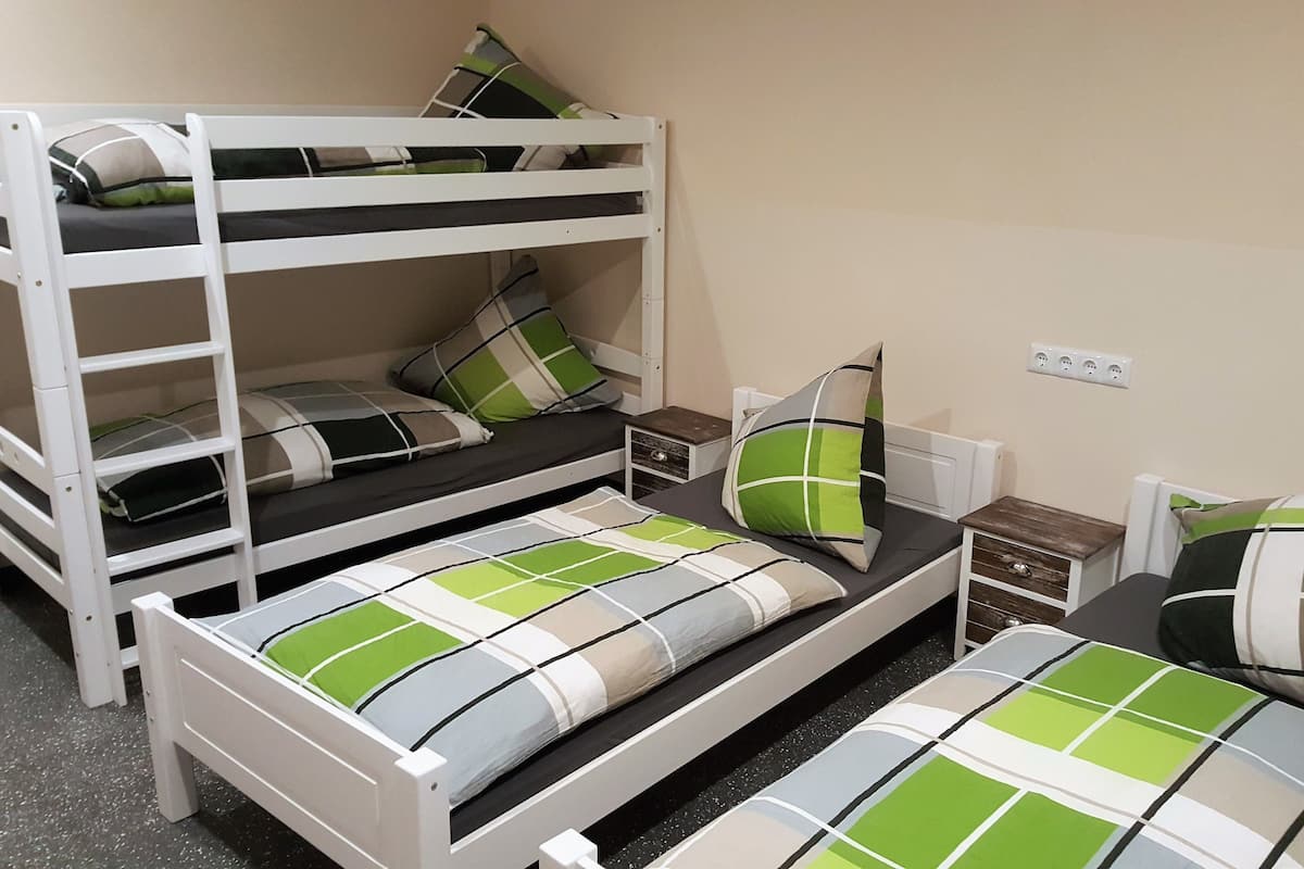 Quarto com beliche, duas camas, cada uma com travesseiro e mesa de cabeceira.