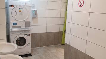 Uma casa de banho moderna com máquina de lavar roupa, duas pias e um sinal de proibido fumar na parede.