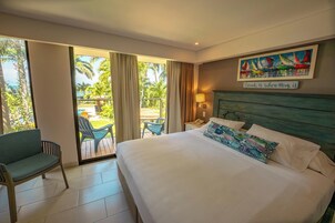 Quarto de hotel com cama, uma cadeira, um quadro e vista para o exterior.