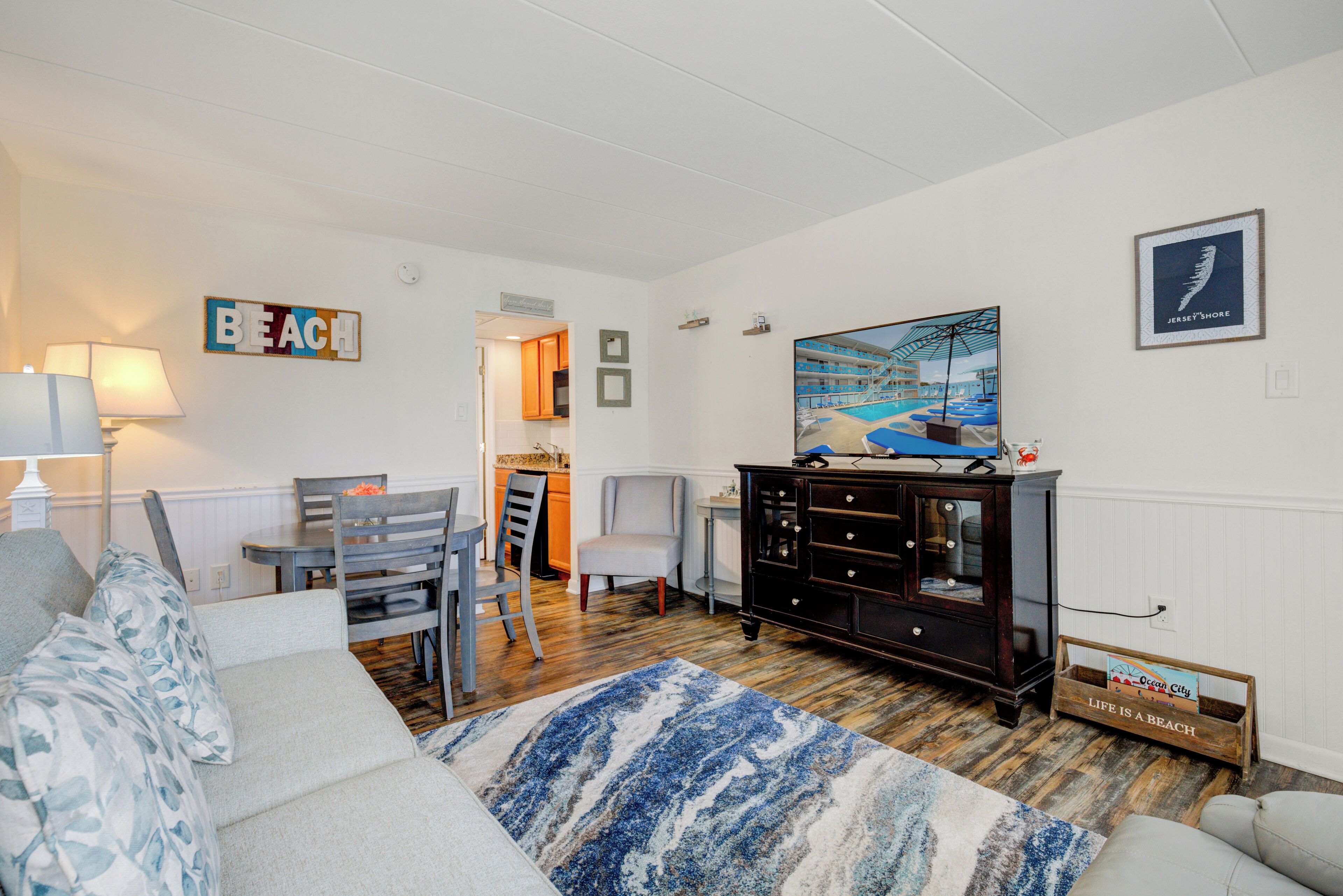 Uma sala de estar com sofá, cadeiras, um armário de madeira e um quadro.
