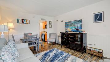 Uma sala de estar com sofá, cadeiras, um armário de madeira e um quadro.