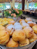 Buffet com diversos doces, incluindo donuts e outros produtos de panificação, dispostos numa bandeja.