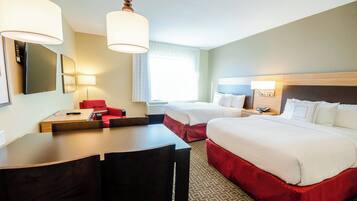 Quarto de hotel com duas camas, uma escrivaninha, uma cadeira, uma televisão e uma janela com cortinas.