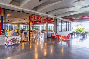 Um restaurante moderno com área de recreação infantil, grandes janelas e diversos tipos de assentos.