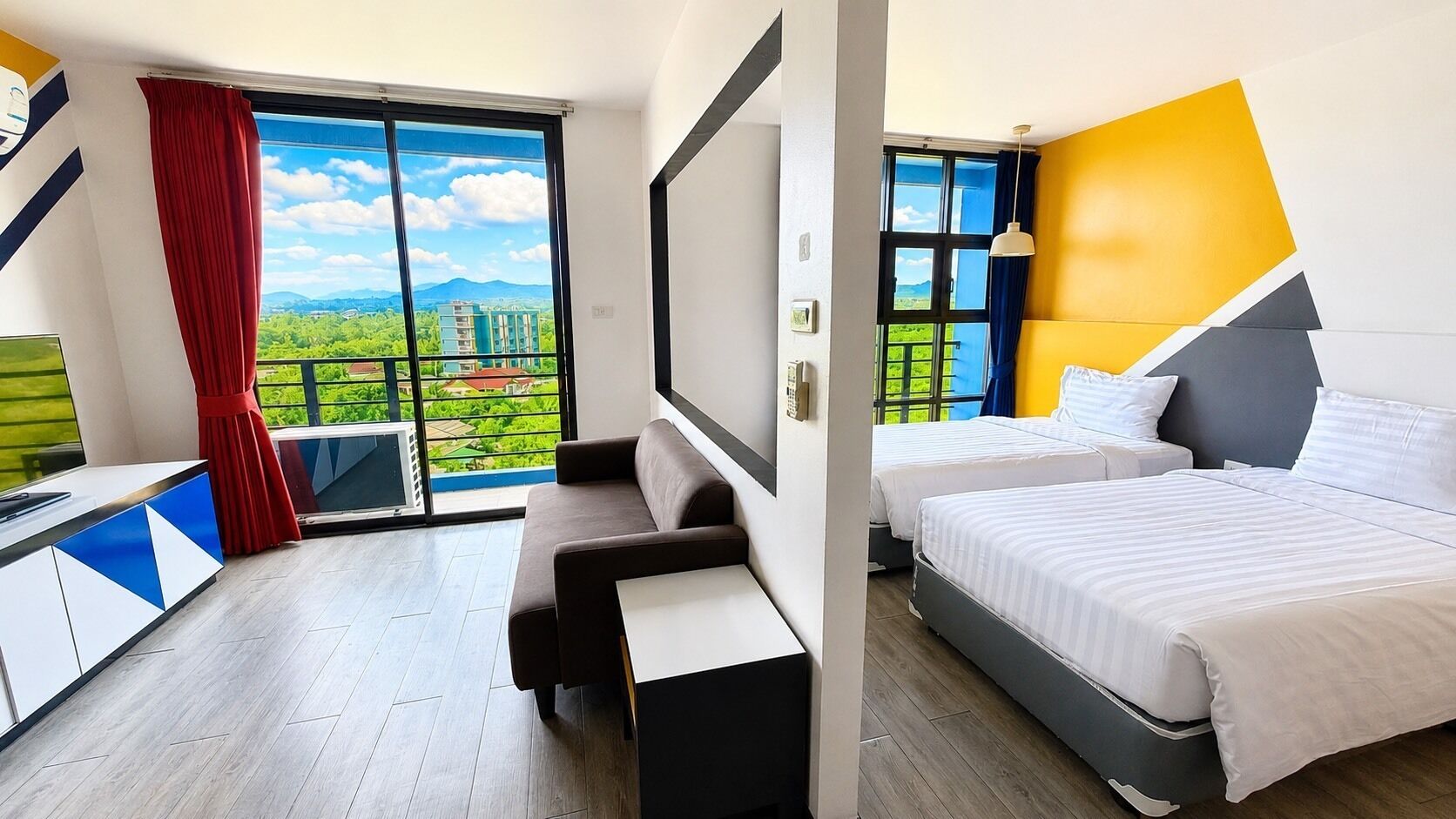 Quarto de hotel com uma janela grande, cama, escrivaninha e área de estar.