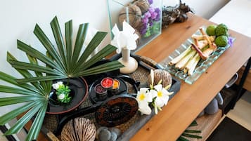 Uma mesa de madeira com uma bandeja de comida, uma planta em vaso e objetos decorativos.