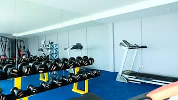 Uma academia com um banco, halteres, esteira e aparelhos de ginástica.
